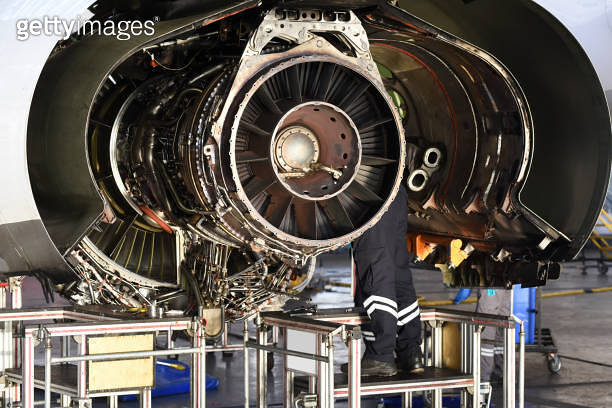 Aircraft engineer repairing and maintaining an airplane jet engine in ...