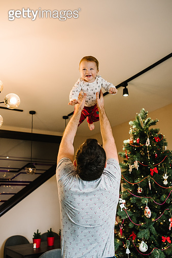 Toddler boy in a Christmas costume and father playing in room. Dad ...