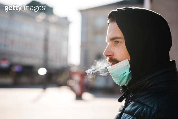 Smoking. Closeup man with mask during COVID-19 pandemic smoking a ...