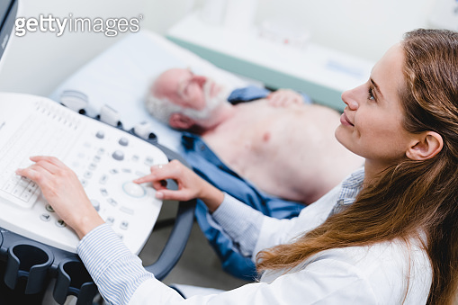 Cropped photo of a woman doctor in the foreground diagnosting senior ...