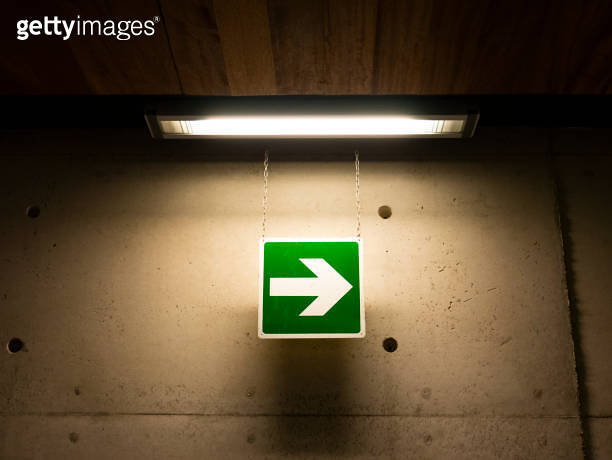 Directional arrow sign illuminated by a neon light from above, right ...