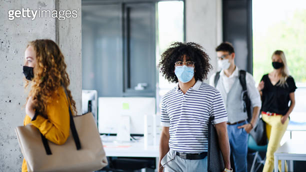Young people with face masks back at work in office after lockdown ...
