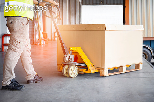 Worker unloading cargo pallet shipment goods, package box, his is using ...