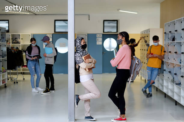 Young students friends with face masks back at college or university ...