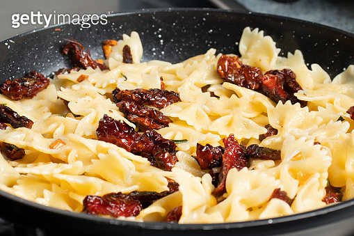 Pan-fried pasta with sun-dried tomatoes and garlic. Stages of cooking ...