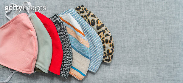 Face masks layered on grey textile background. Many colors of fabric ...