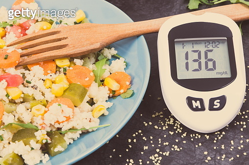 Glucose meter with result sugar level and salad with couscous and ...