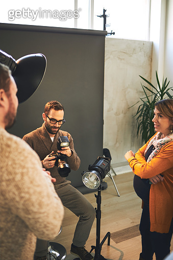 Young attractive bearded tutor sitting on chair in studio, holding ...