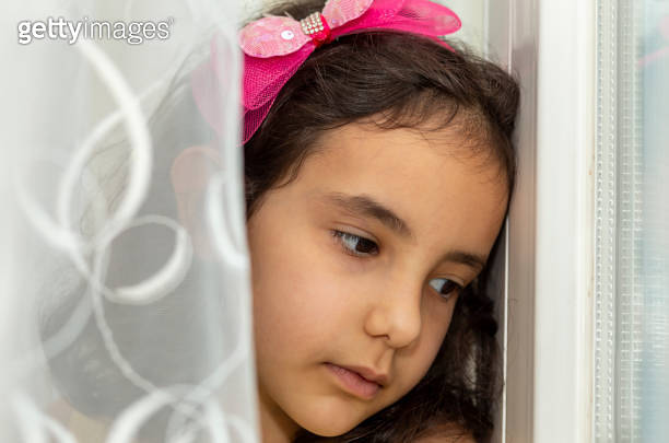 Unhappy and bored little girl waiting for behind the window 이미지 ...
