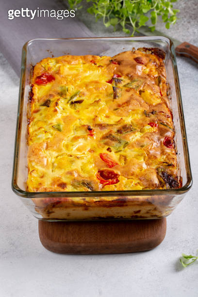 Vegetable clafoutis in glass baking dish on concrete background, savory ...