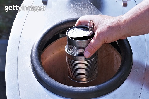 A man dropping empty cans into container for separation of home waste ...