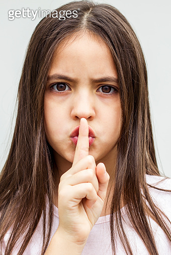 Emotional beautiful little girl with finger on lips making quiet ...