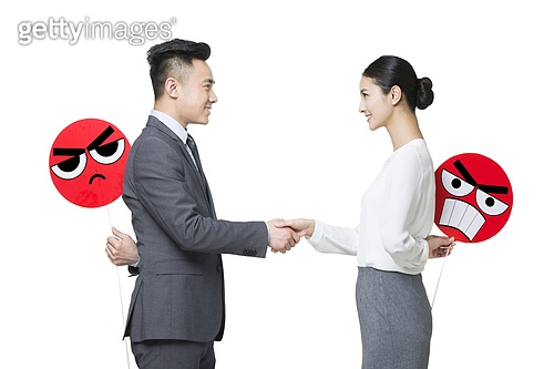 Business person shaking hands with angry emoticon faces behind their ...
