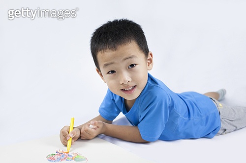 Happy little Chinese boy coloring while lying on the floor 이미지 ...