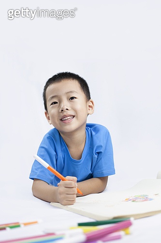 Happy little Chinese boy coloring while lying on the floor 이미지 ...