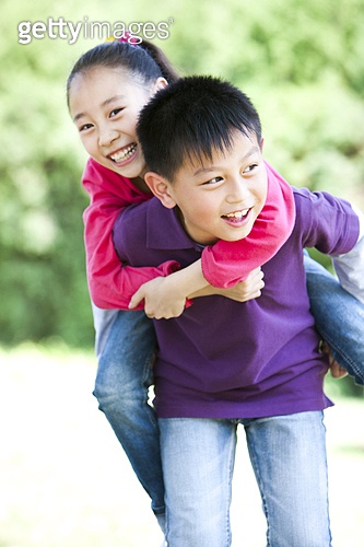 Young boy giving girl piggyback ride 이미지 (a10724071) - 게티이미지뱅크