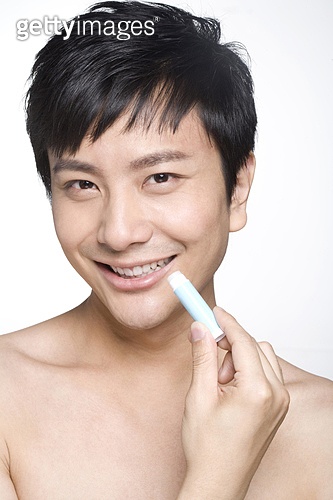 Young man using lip balm 이미지 (a10728989) - 게티이미지뱅크