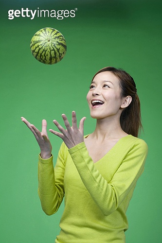 Woman in green throwing a melon 이미지 (a10733575) - 게티이미지뱅크