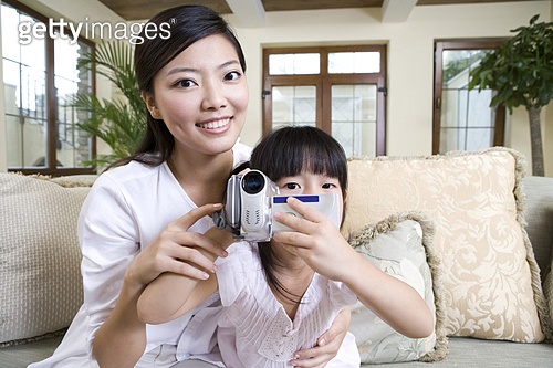 Mother and daughter using digital video camera (a10780024) - 게티이미지뱅크