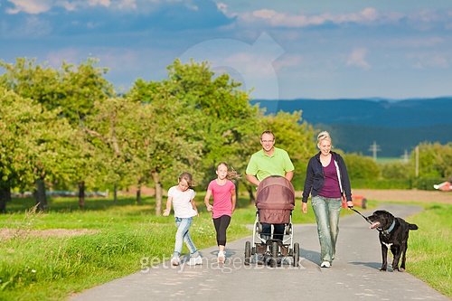 Family with three children (one baby lying in a baby buggy) walking ...
