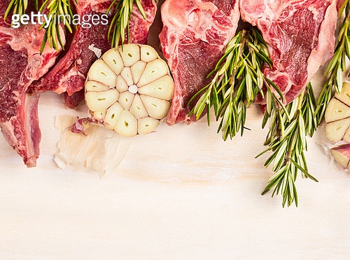 Raw lamb meat with garlic and rosemary on white wooden backgound, top ...
