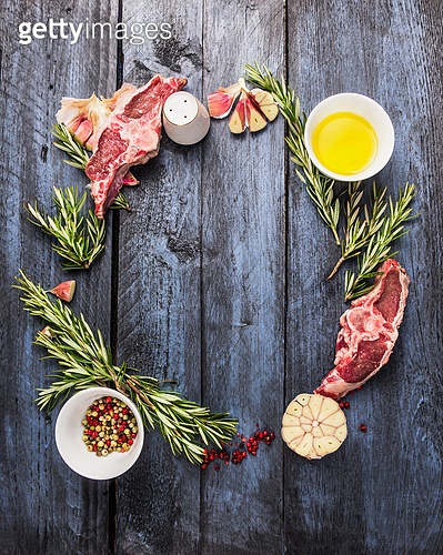 raw lamb meat circle frame with rosemary herbs, garlic and oil, on blue ...