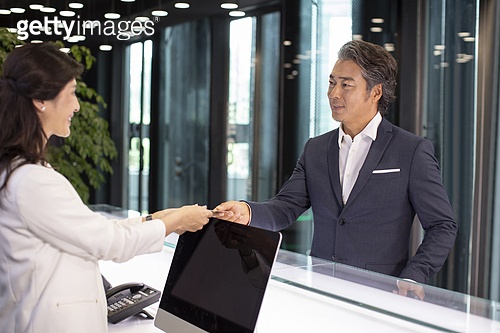 Chinese receptionist giving business card to businessman 이미지 (a12300474 ...