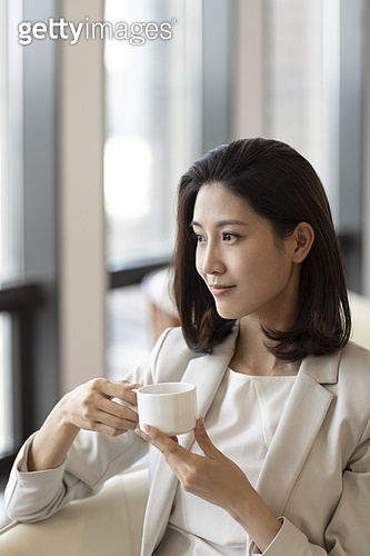 Confident Chinese businesswoman drinking coffee in coffee shop 이미지 (a12302629) - 게티이미지뱅크