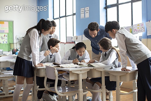 Teacher talking with students in classroom 이미지 (a12302832) - 게티이미지뱅크