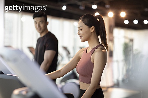 Young Chinese couple running on treadmill at gym 이미지 (a12303730) - 게티이미지뱅크