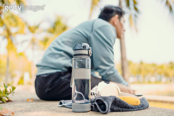 Water bottle, banana, headphone and towel on the ground beside young ...