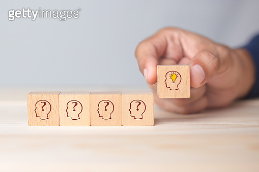 Hand business picked wooden cube block with head human symbol and light ...