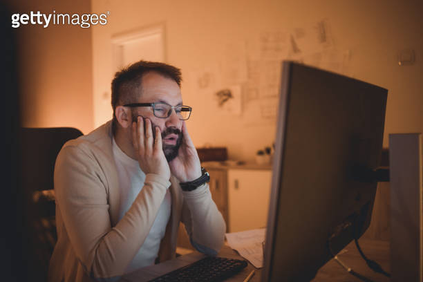 The man uses the computer at night, working late into the night. Late ...