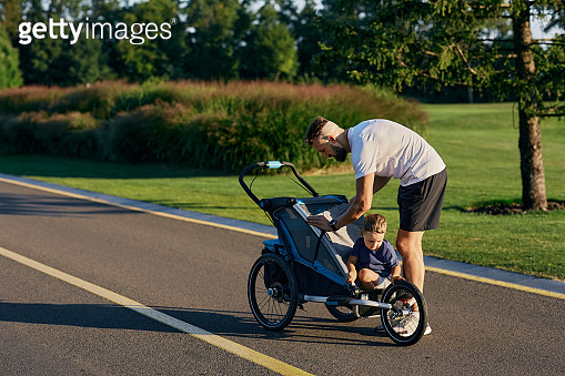 Father with his little son with jogging stroller during morning workout ...