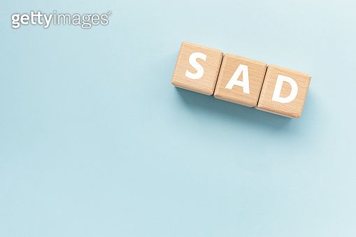 Text SAD on wooden cubes on blue background. Abbreviation of 'Seasonal ...