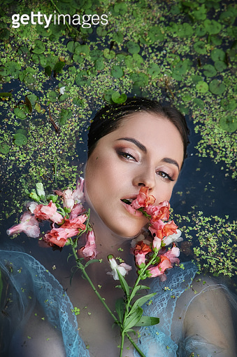 Art beautiful romantic woman lies in swamp in blue long dress with ...