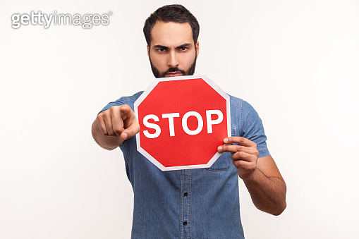 Strict angry man with beard holding stop sign and pointing at camera ...
