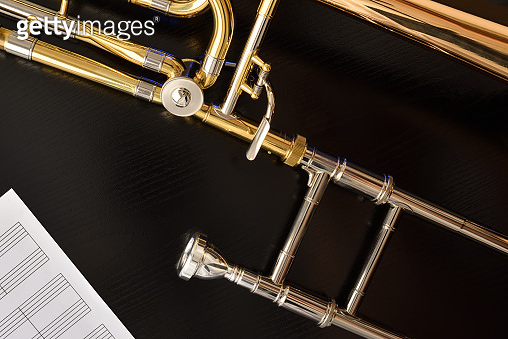 Trombone mouthpiece and pipe detail with stave sheets on black ...