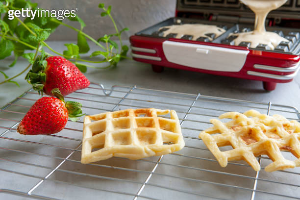 Close-up of waffel maker and soft Viennese waffles on the wire rack ...