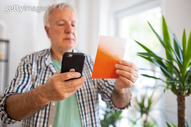 Senior man looking at flyer and ordering delivery using mobile app on ...