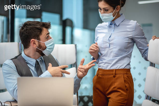 Two young responsible colleagues talking in office with their ...