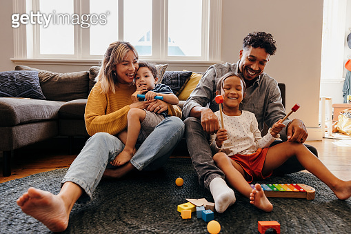 Loving parents having fun with their kids in the living room at home ...