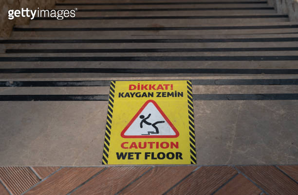 Wet floor caution sign on walkway near the building after raining ...