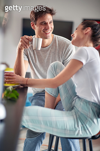 A young couple in love chatting and enjoying a coffee before breakfast ...