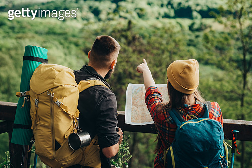 Hikers using map and pointing to the right direction while spending ...