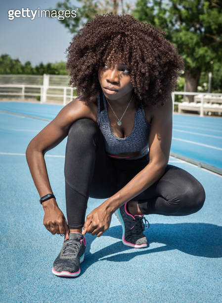 Young black woman athlete with afro hair looking to the side crouching ...