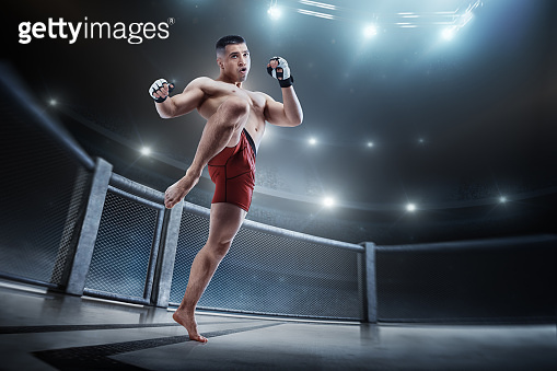 Knee kick. Male fighter with a knee kick. Sport. Fighter in the octagon ...