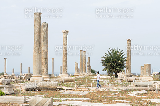 Tourist visiting the Roman ruins colonnade in Al Mina archaeological ...