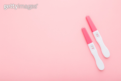Pregnancy tests with one stripe and two stripes on light pink table ...