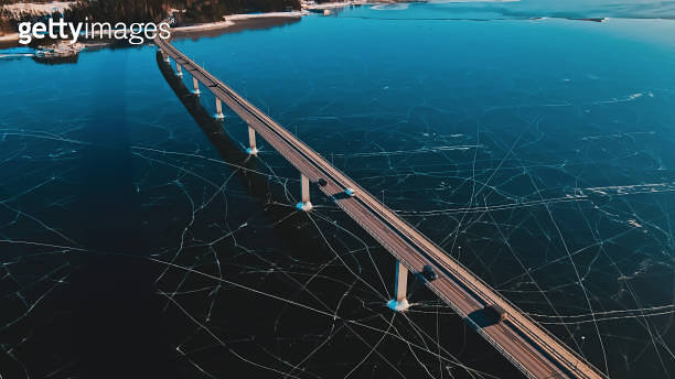 Highway bridge spanning a large body of frozen water covered in thick ...